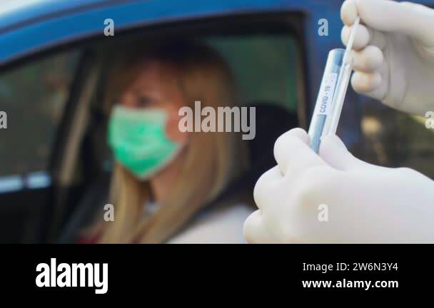 Woman sitting in car, waiting for medical worker to perform drive-thru ...