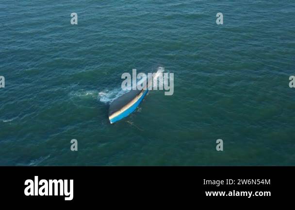 ship sunk at sea. The drone flies round an inverted ship in the ocean ...