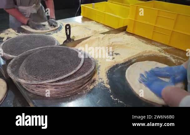 Female Workers Quickly making a Dough for Pizza on a industrial Bakery ...