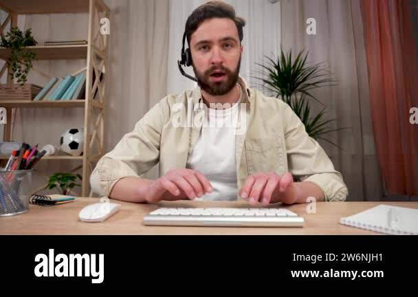 A man speaking on a webcam in wireless headphones with a microphone ...