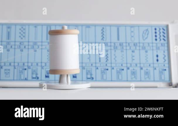 Spool with white thin thread on working a new sewing machine. Spool ...