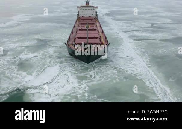 Aerial above epic huge steel icebreaker breaks ice by bow of ship and ...