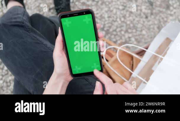 Woman hands doing scrolling, swiping, tapping gestures on the smartphone with green mock-up ...