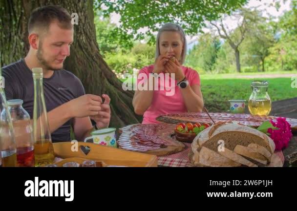 Man and woman eat cured meat and cheese from charcuterie platter ...
