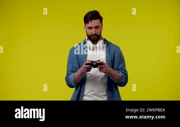 A man with big white headphones around his neck plays a video game with ...