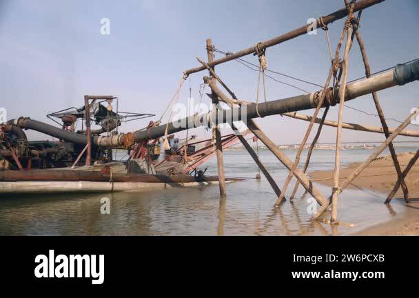 Dredging boat by the riverbank with pipeline system hold with bamboo ...