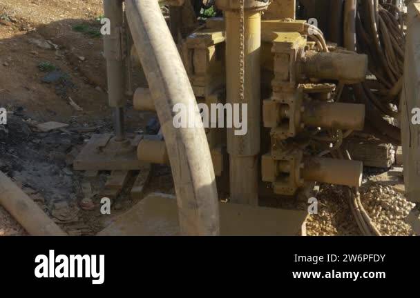 CLOSE UP: Heavy industrial rig bores a hole in the ground for a ...