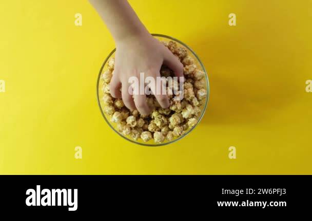 Family hands grab popcorn . Glass bowl of sweet popcorn at yellow ...