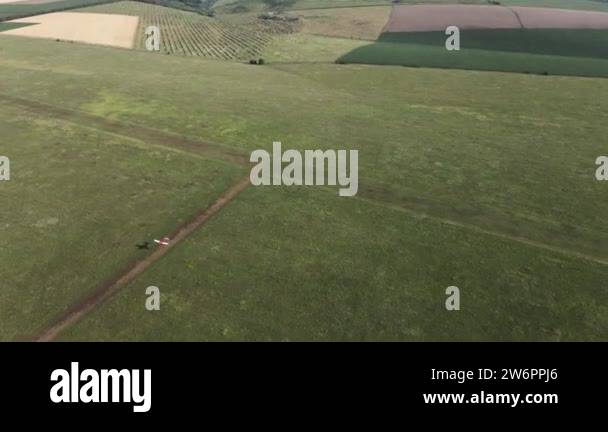 Aerial video showing a small red plane landing on a field. The moment ...