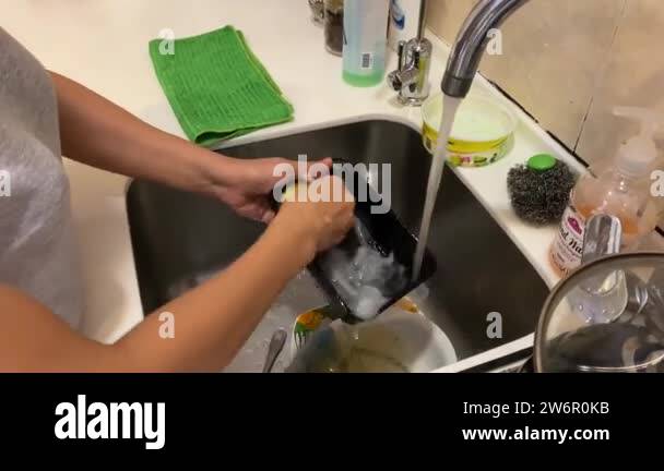 woman washing black takeout plastic packaging for food to reuse ...
