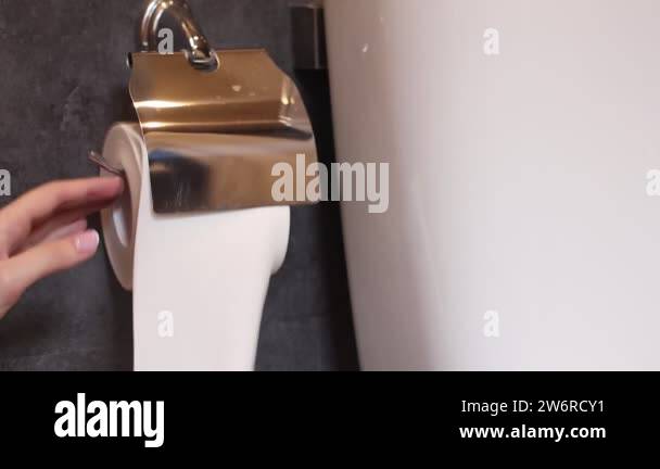 Woman using toilet paper in bathroom. Roll of toilet paper in the ...