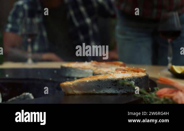 Woman chef salting fish on grill outside. unknown woman pouring salt on ...