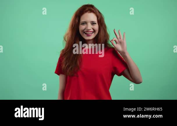 Pretty woman showing ok, okay sign over green studio background ...