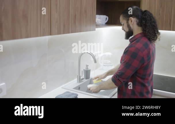 Husband washing dishes in the kitchen, division of household chores in ...