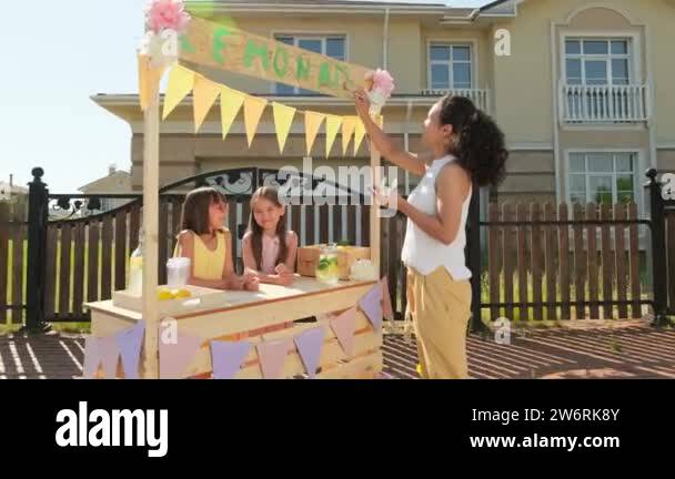 Dollying-in medium shot of joyful woman decorating wooden diy lemonade ...