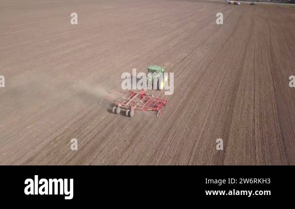Top down aerial view of green tractor cultivating ground and seeding a ...