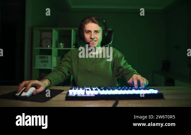 Positive guy gamer streams game in a room with purple light and looks ...