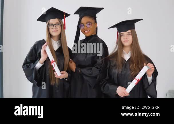 Three young happy graduate women of different nationalities stand ...