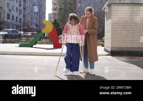 Mom Helps Daughter Learn To Walk On Crutches Plaster On Your Feet