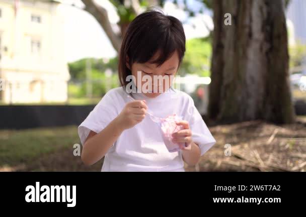Asian chinese child girl eating ice cream hungrily for the first time ...
