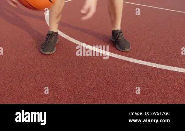 Legs man practicing ball skills by rolling a basketball between his ...
