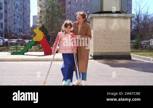 Mom Helps Daughter Learn To Walk On Crutches Plaster On Your Feet