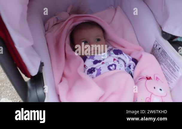 Young baby moving and making funny face expressions lying in the pram ...