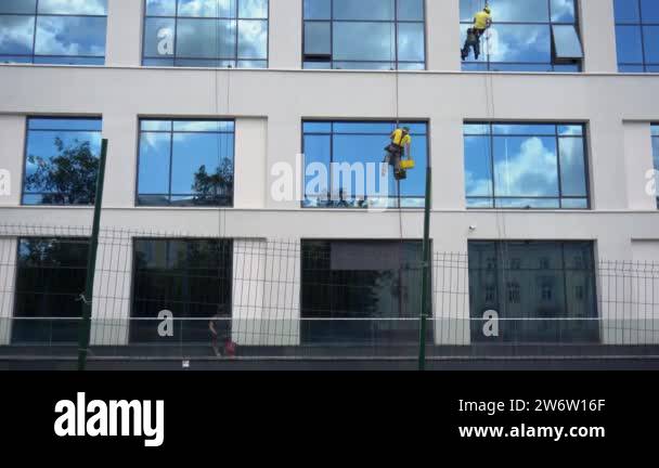 Glass window cleaners washers work outside the building. Professional ...