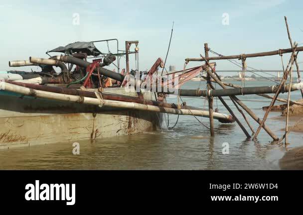 Dredging boat by the riverbank with pipeline system hold with bamboo ...
