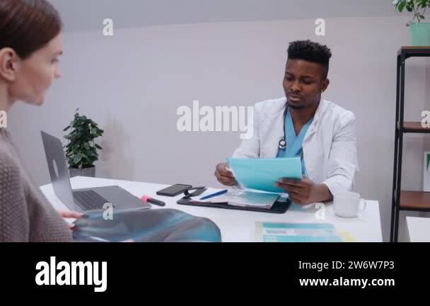 Doctor sees patient, looking at x-rays, wearing medical gown and ...
