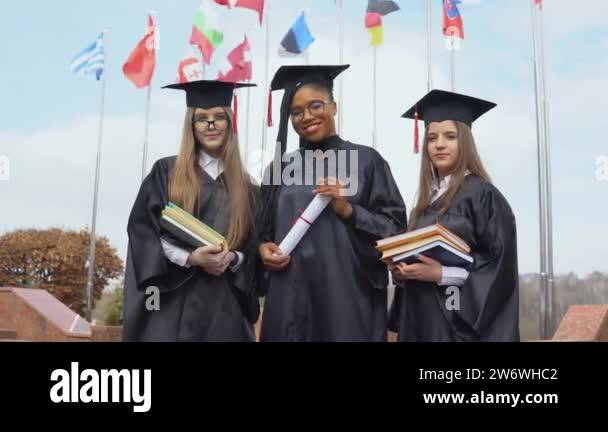 Three young women university graduates of different nationalities smile ...
