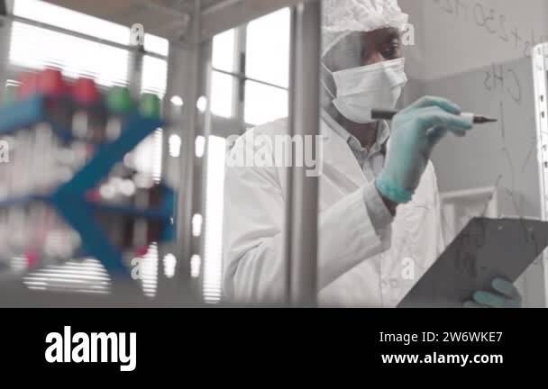 Low angle of African American male scientist wearing medical gown, hat ...