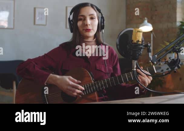 Beautiful female musician in headphones looking at camera, playing the ...