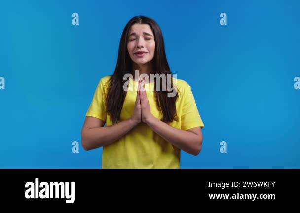Pretty woman praying with hands on blue background. Girl begging God ...