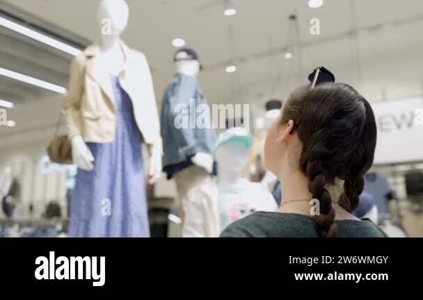 A woman looks at a mannequin with clothes in a store. Head close-up ...