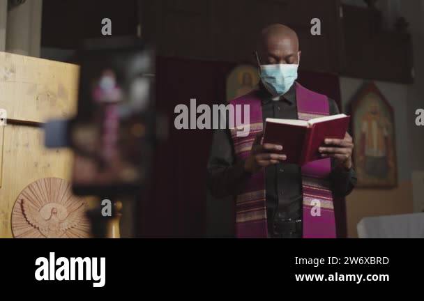 Racked focus shot of African-American pastor wearing medical mask ...