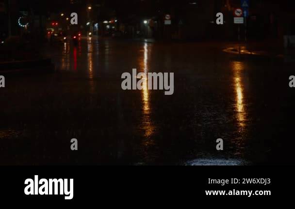 Close-up at night, drops of summer or autumn rain fall on the asphalt ...
