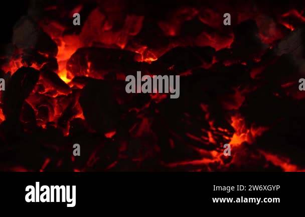 Red-hot coals burn in the fireplace. The flame of the fire burns slowly ...