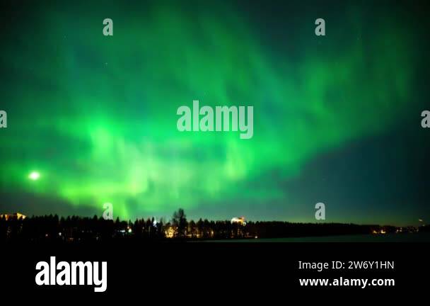 Green aurora northern light dancing under a starry and moonlit sky on a ...
