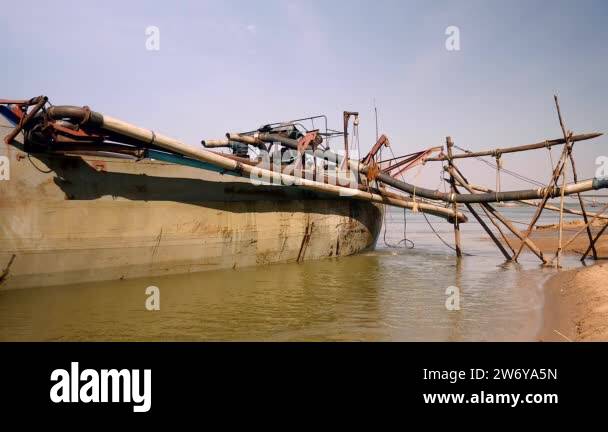 Dredging boat by the riverbank with pipeline system hold with bamboo ...