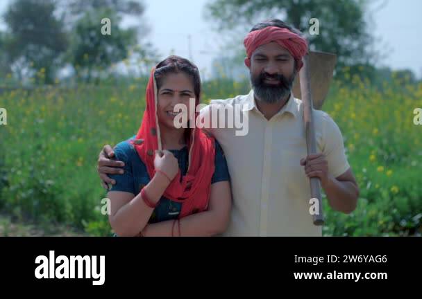 A rural villager with an agricultural tool standing with his wife in ...