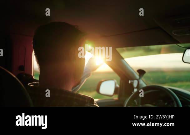 Free young man, driving car, catching sunlight and wind from car window ...