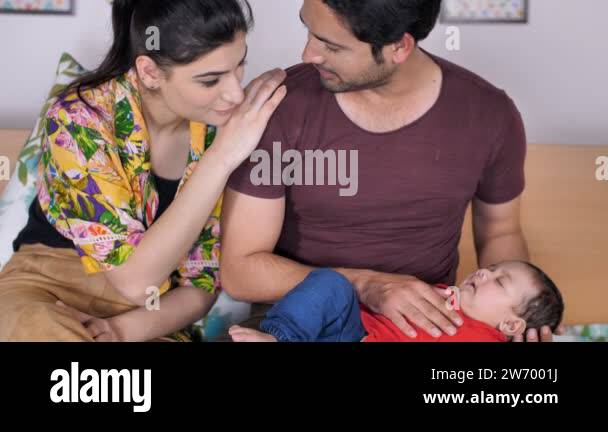 A loving Indian father patting his little daughter to sleep on his lap ...