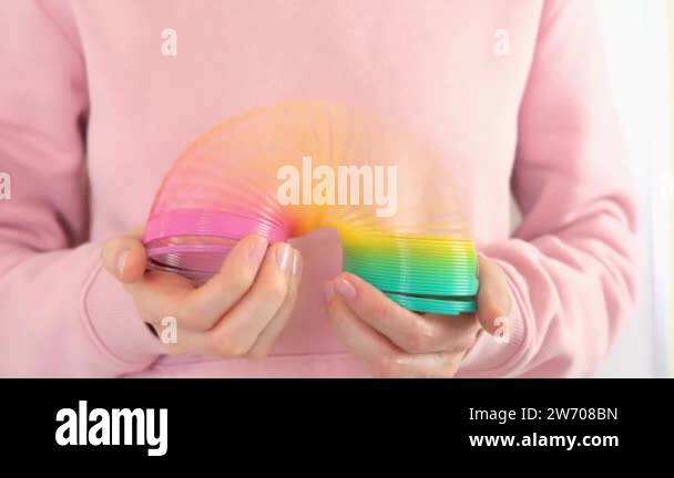 Plastic rainbow toy in hands. Colored spiral for games and tricks ...
