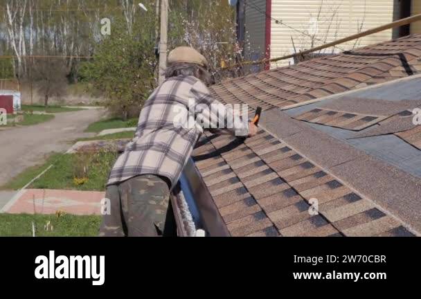 Laying of soft tiles. Bitumen roofing. Hammering nails with a hammer ...