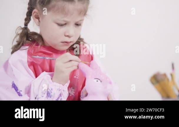 Little girl painting paper mache figurine at homeschooling art class ...