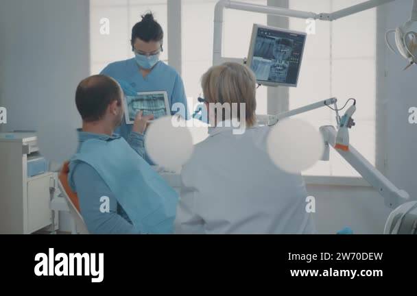 Dentistry team showing teeth x ray scan to patient with toothache Stock ...