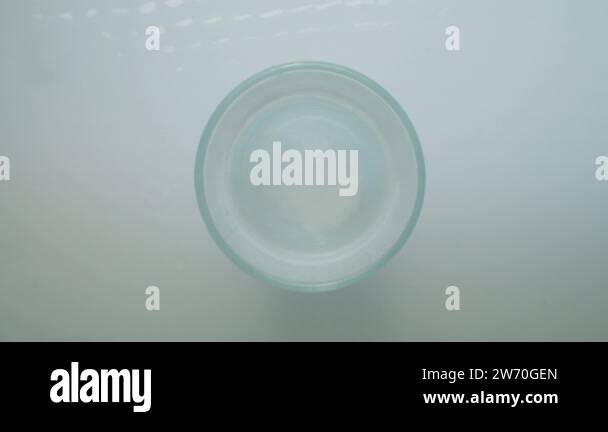 Zoom in top view shot of hand throwing effervescent tablet into glass ...