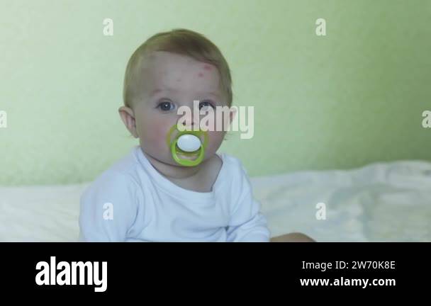Defocused face of cute funny baby with blue eyes posing with a pacifier ...