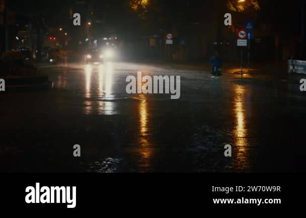 Close-up at night, drops of summer or autumn rain fall on the asphalt ...